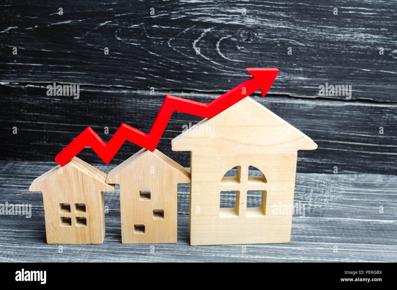Wooden houses stand in a row from small to large with a red arrow up ...
