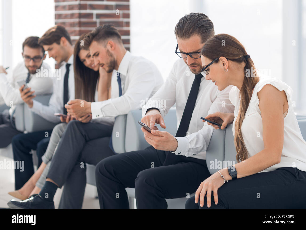 employees of the company using their smartphones sitting in the office ...