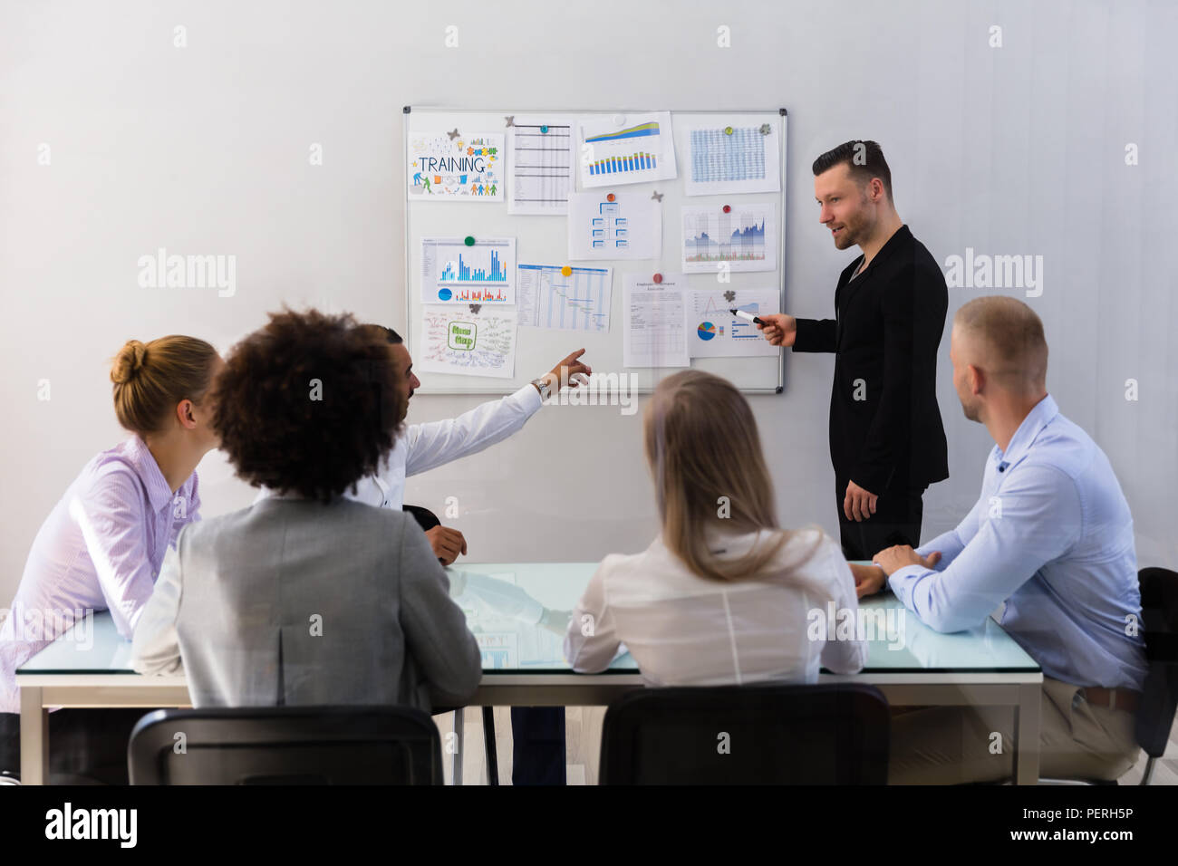 Young Businessman Explaining Graphs To His Colleagues At Workplace ...
