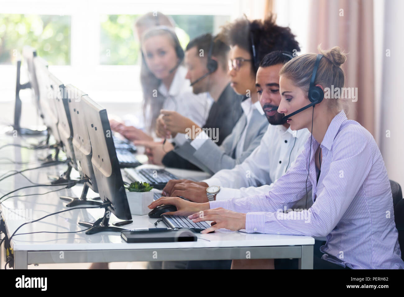 Young Customer Service Executives Using Earphones Working In Call ...
