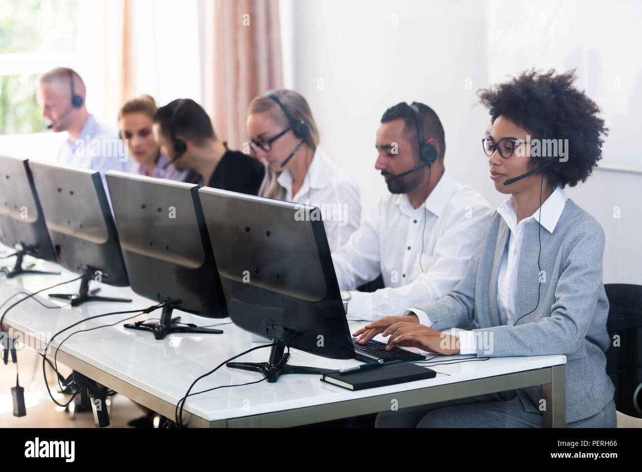 Young Customer Service Executives Using Earphones Working In Call ...