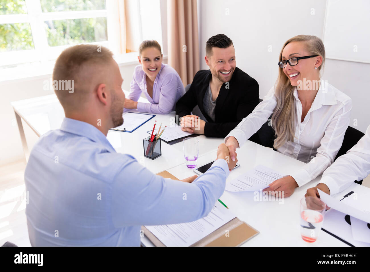 Smiling Young Man Shaking Hands With Female At Interview Stock Photo ...