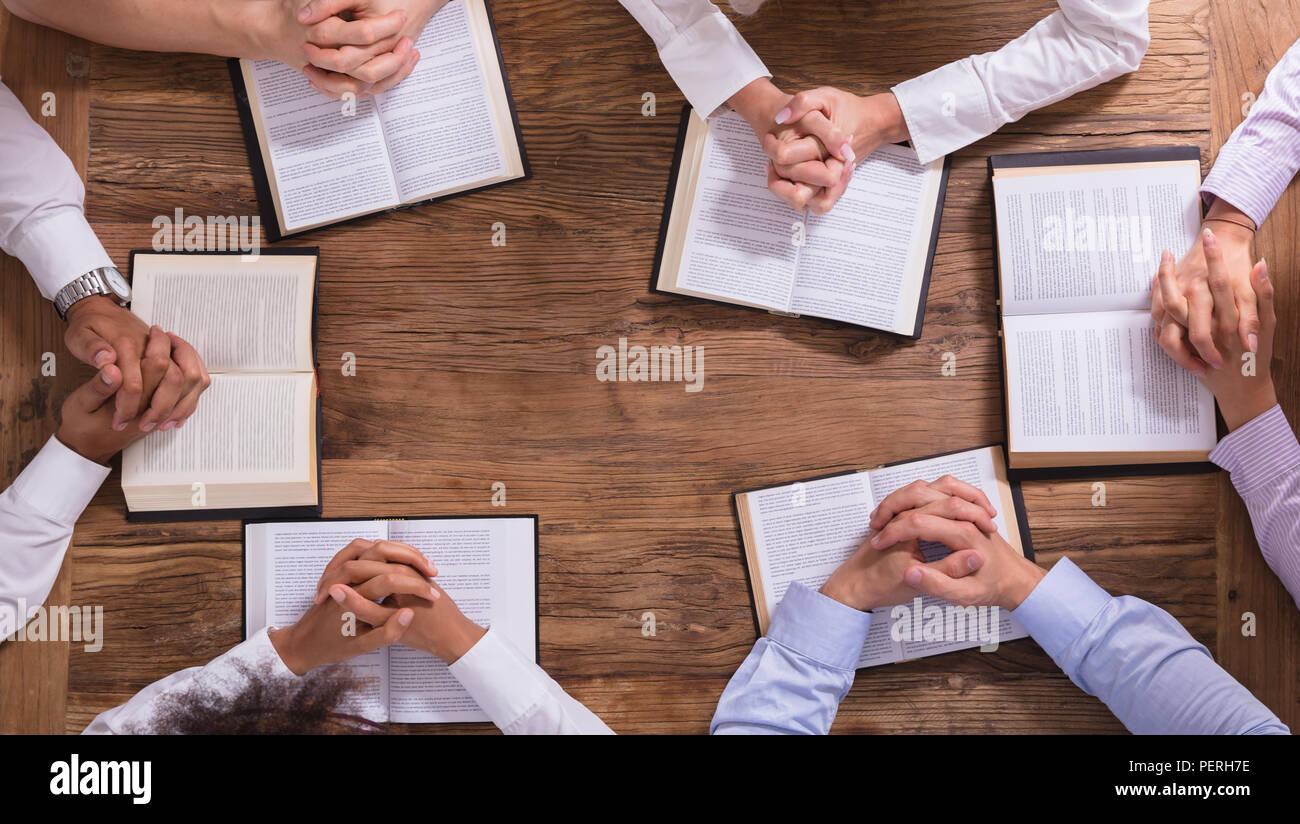 High Angle View Of People's Praying Hands On Holy Bible Stock Photo - Alamy