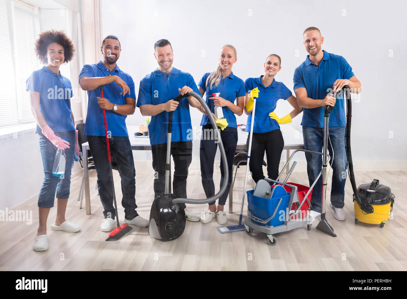 Portrait Of Happy Male And Female Janitors With Cleaning Equipment ...