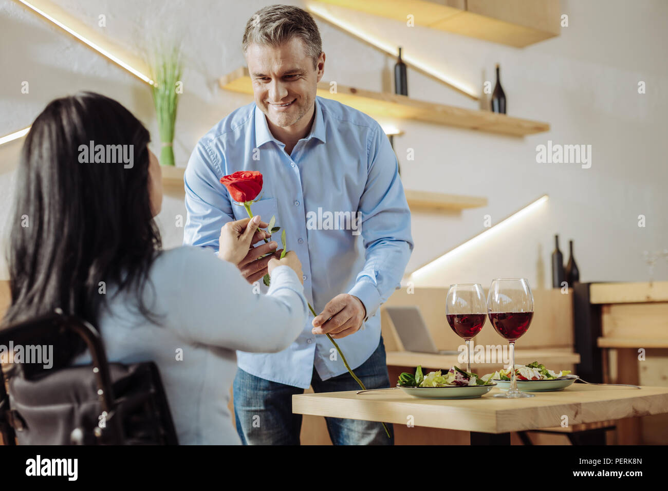 Cheerful man presenting a flower to a woman Stock Photo - Alamy