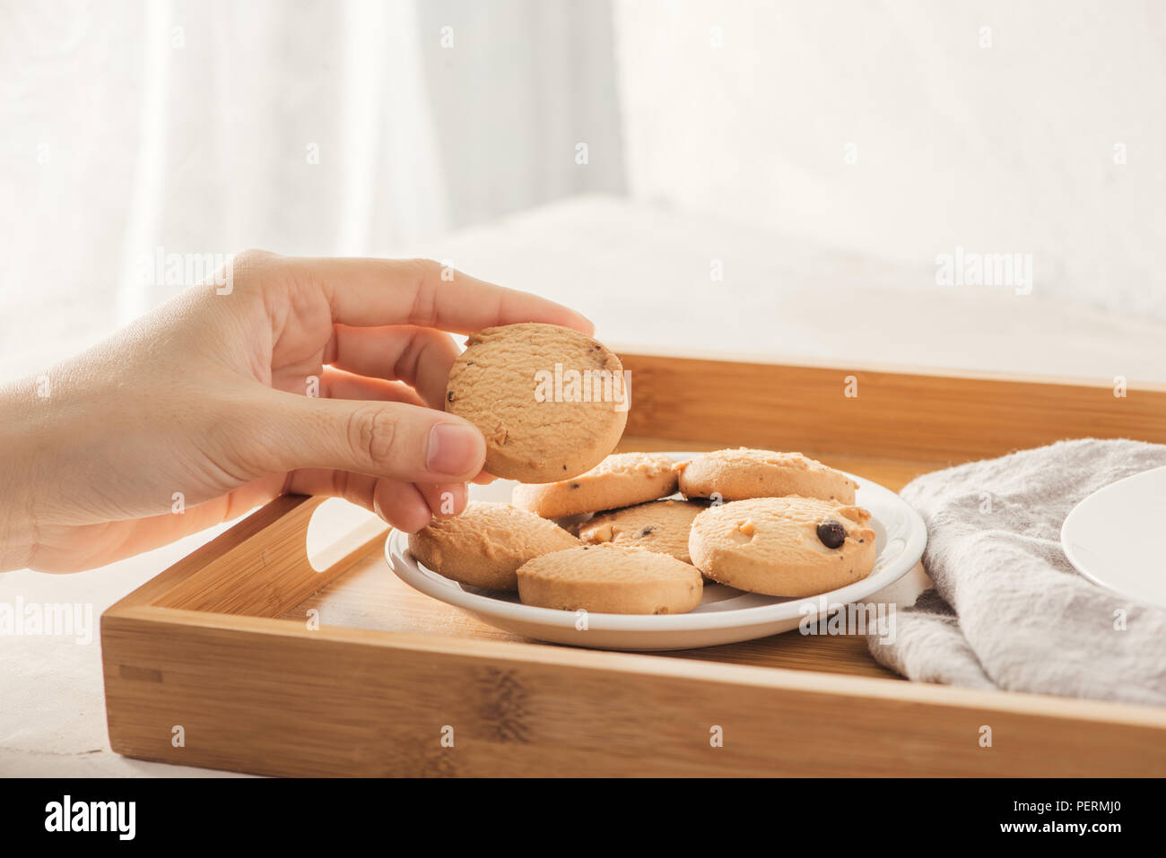 Hand picking cookie from plate in tray Stock Photo - Alamy
