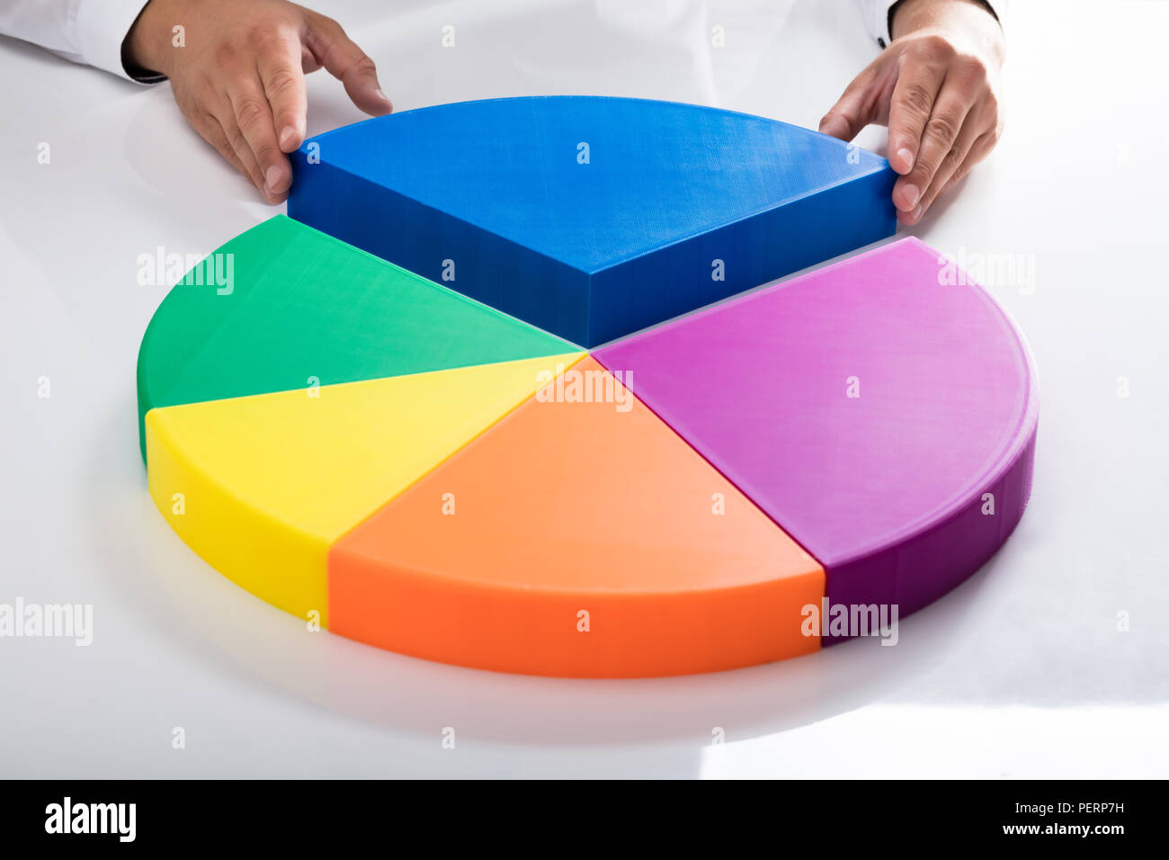 Human hand placing final blue piece into multi colored pie chart Stock ...