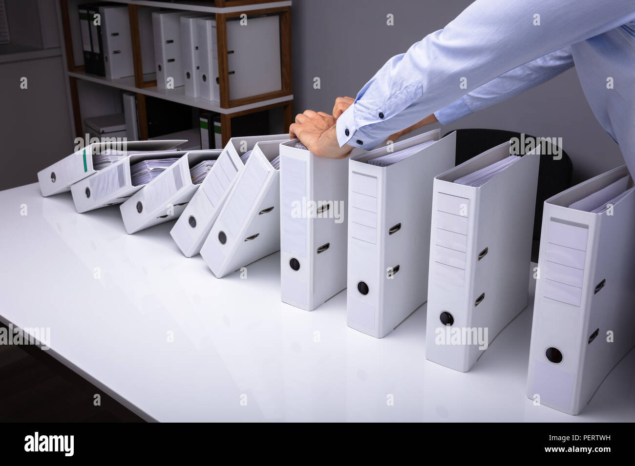 Man Stopping Falling Files On Desk In Office Stock Photo - Alamy