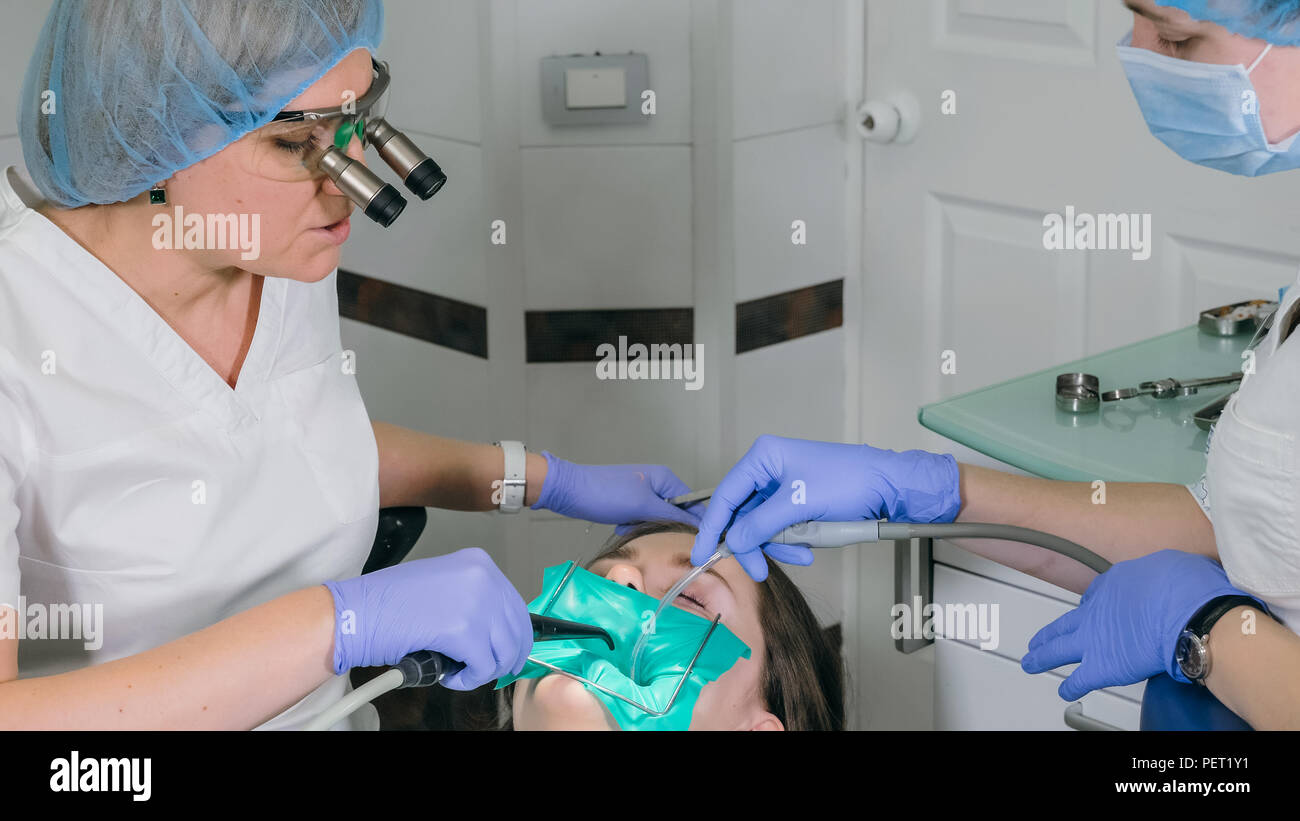 Woman at dentist clinic gets dental treatment to fill a cavity in a ...
