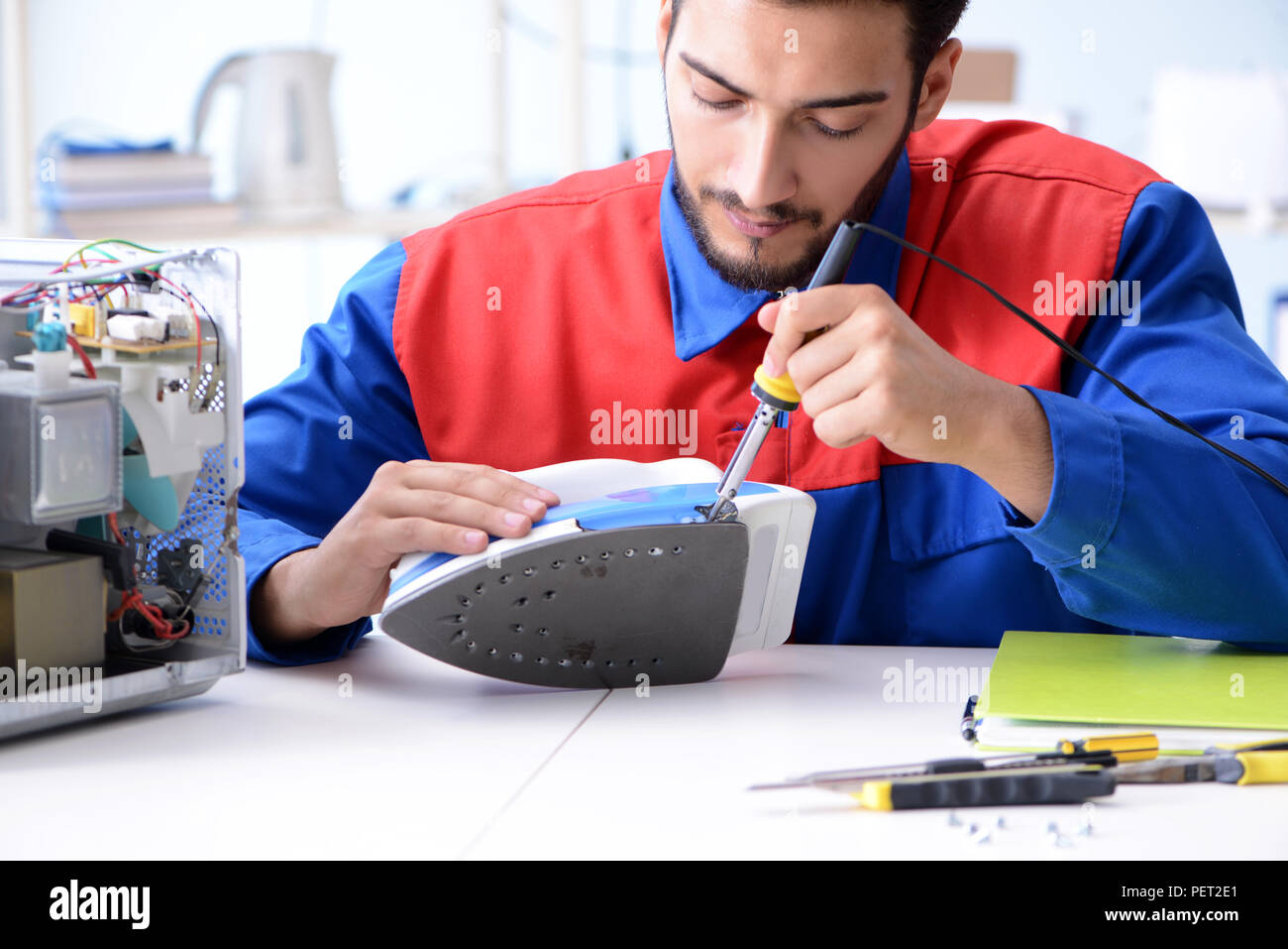 Man repairman repairing iron at service center Stock Photo - Alamy
