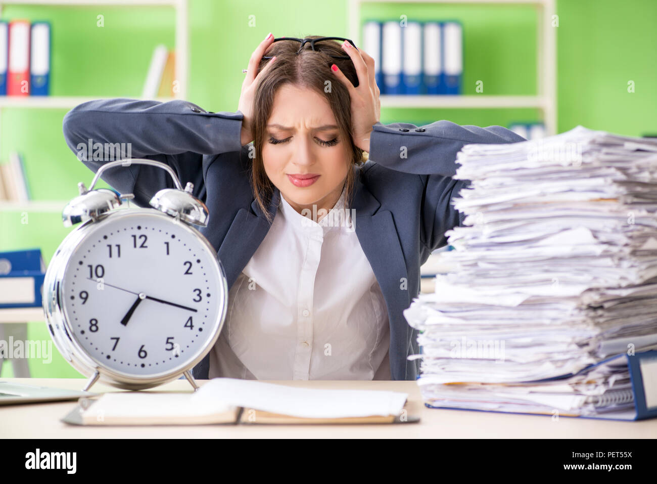 Young female employee very busy with ongoing paperwork in time ...