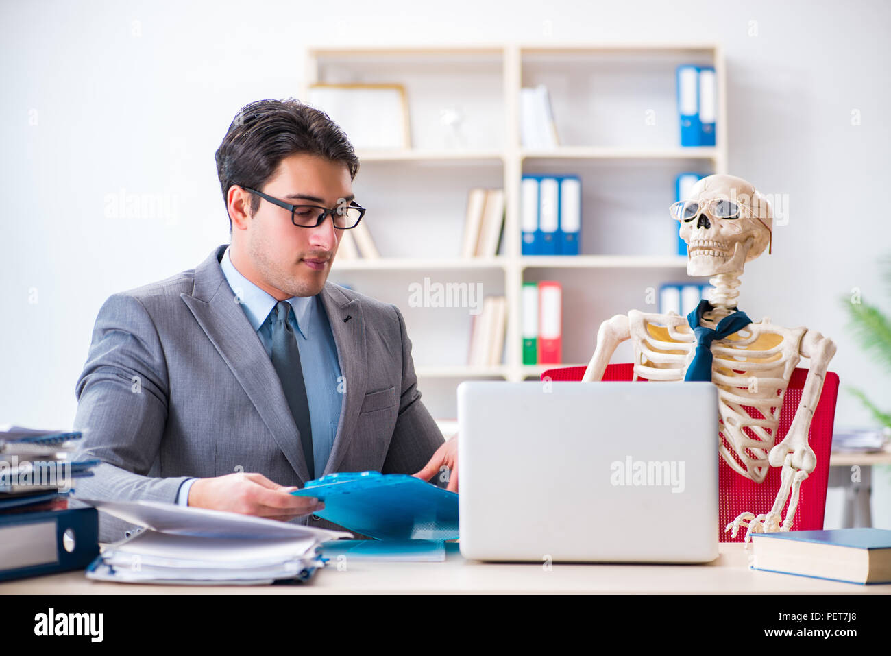 Businessman working with skeleton in office Stock Photo - Alamy
