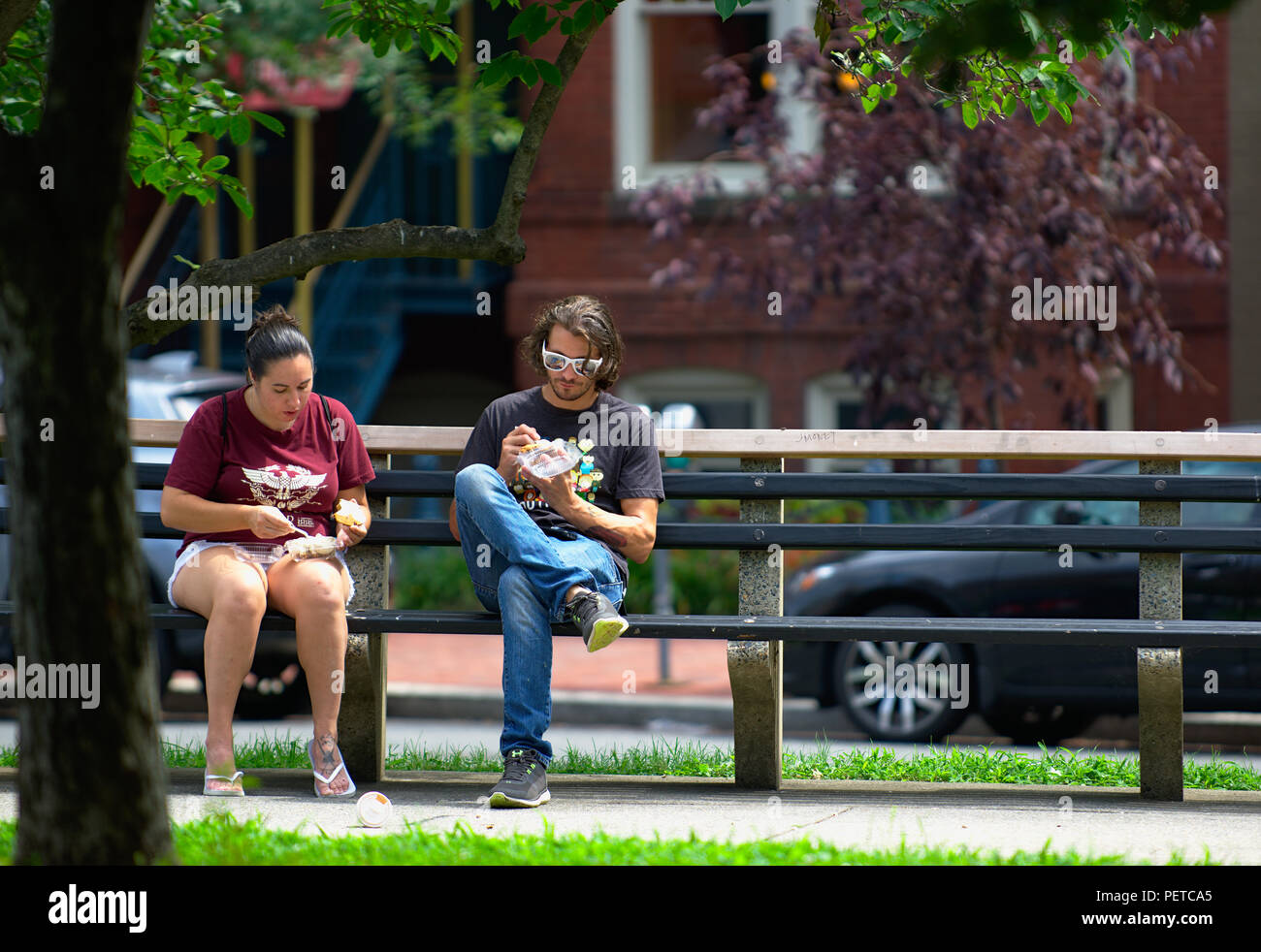 Couple sitting on park bench eating lunch from plastic containers Stock ...
