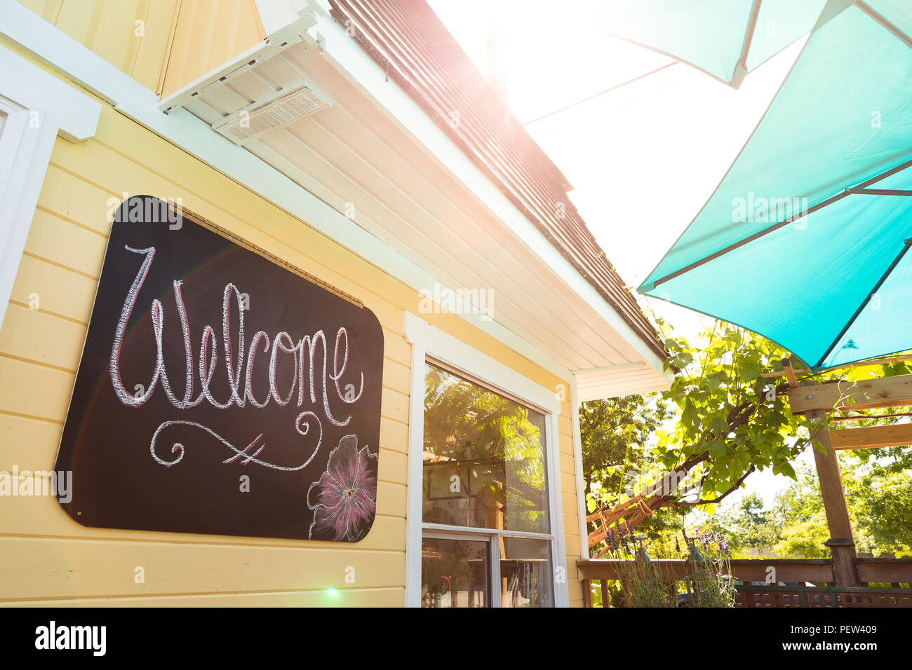 Welcome sign on a restaurant patio with an umbrella and the sun shining ...
