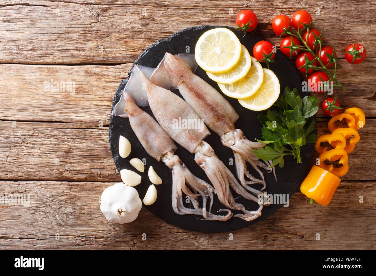Fresh raw squid with tentacles closeup and vegetable ingredients on the ...