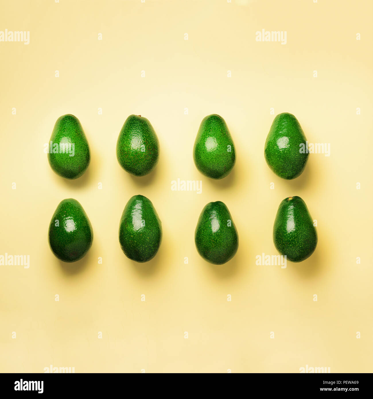 Green avocado pattern on yellow background. Square crop. Top view. Pop ...