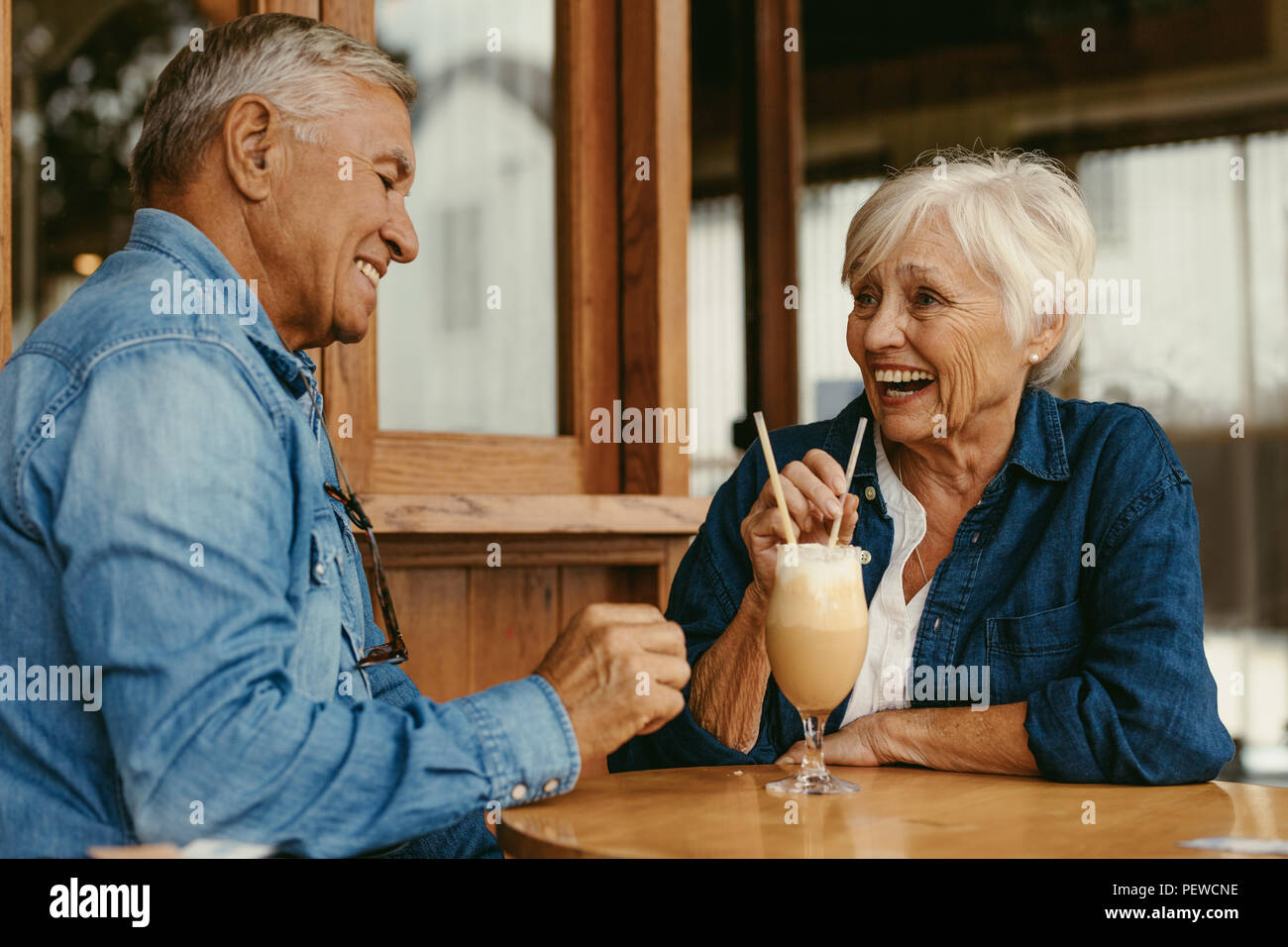 Portrait of cheerful senior couple sitting at table in cafe. Happy old ...