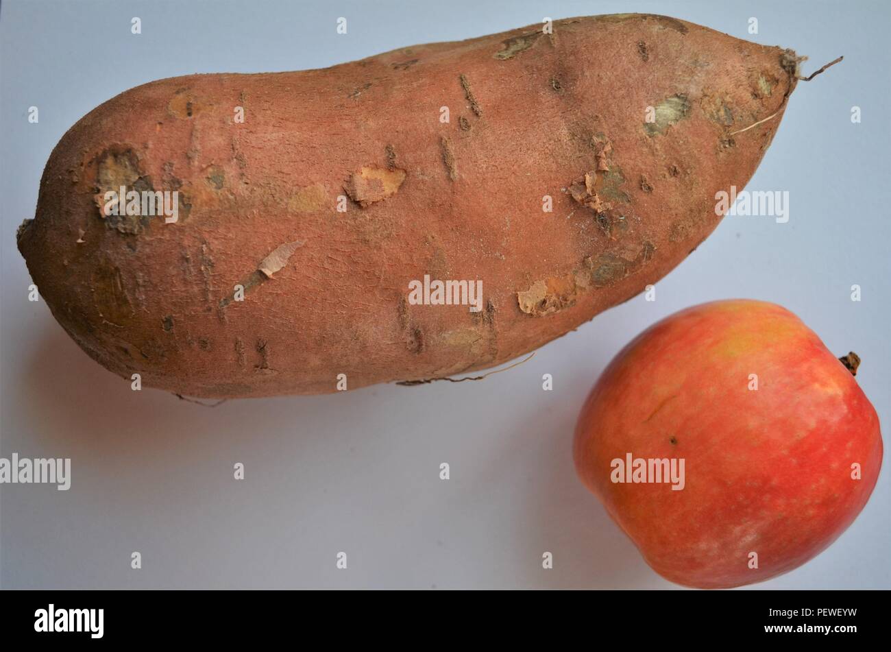 Big sweet potato in comparison with an apple isolated Stock Photo - Alamy