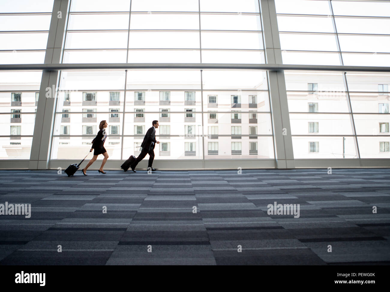 Male and female business people running past a window in the lobby of a ...