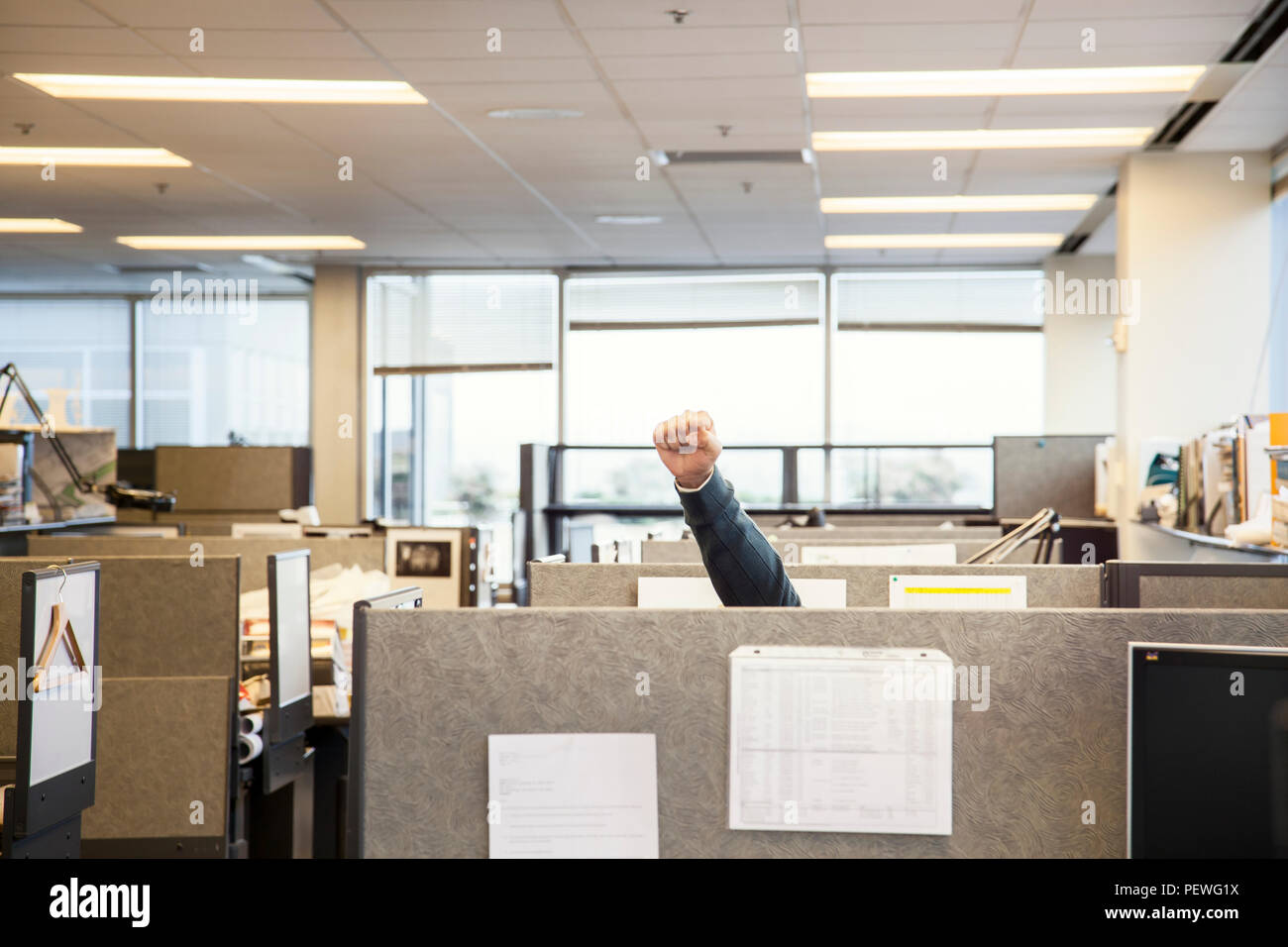 A view of cubicles in an office with a person raising their fist Stock ...