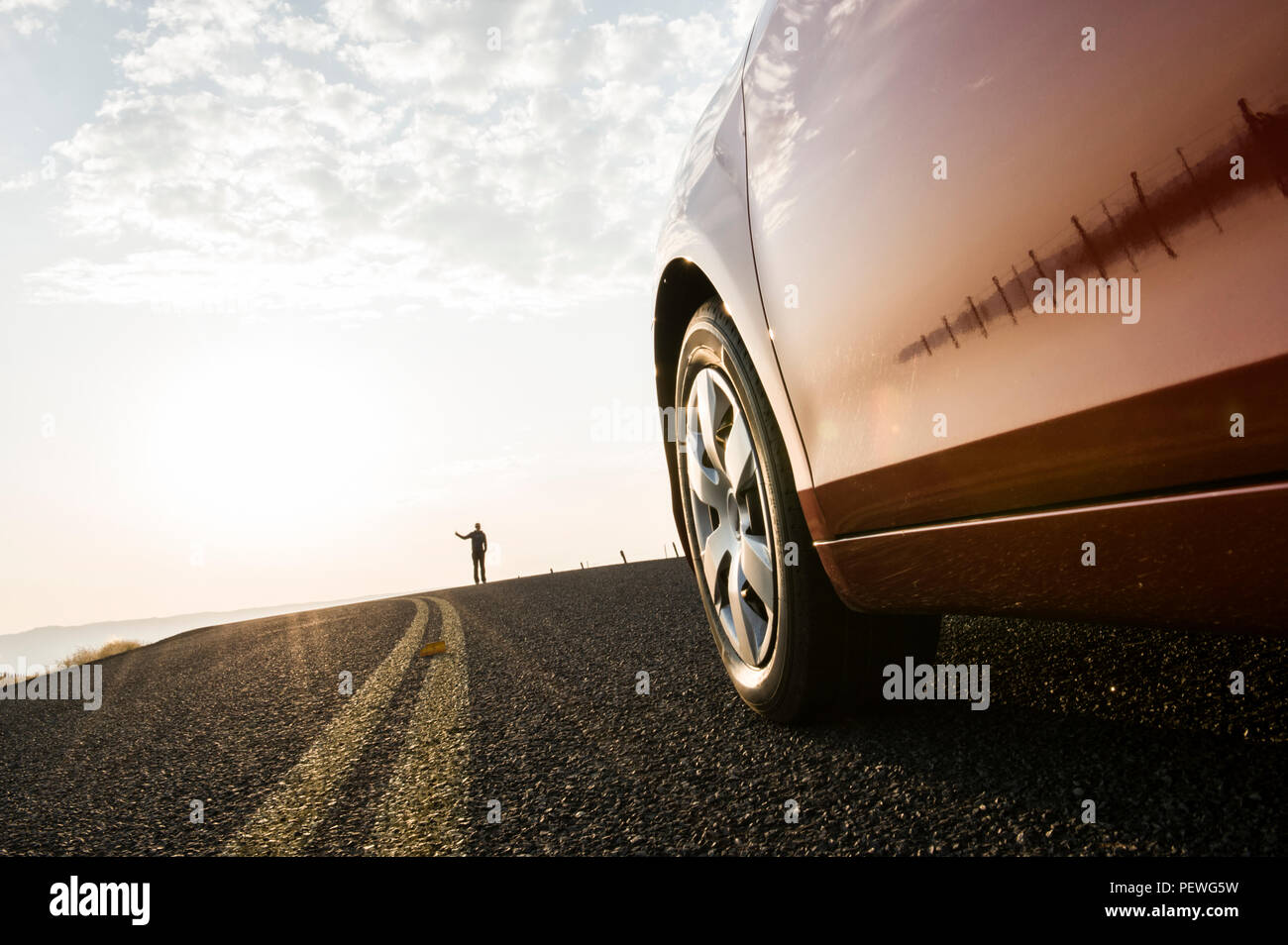 An automobile approaching a person standing on the side of a road Stock ...