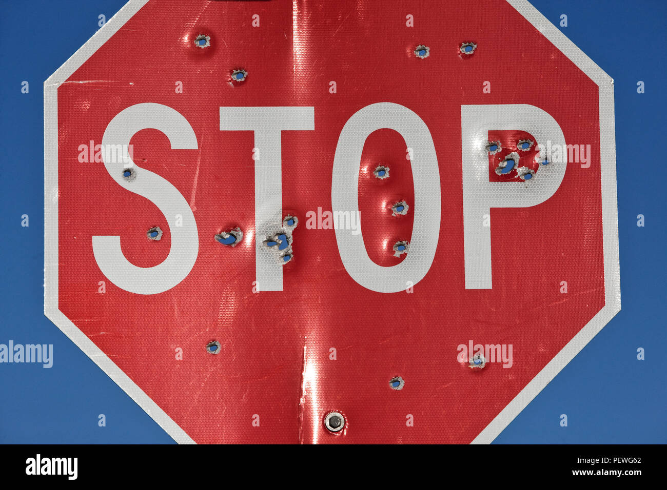 A stop sign that has been shot multiple times with a high powered rifle ...