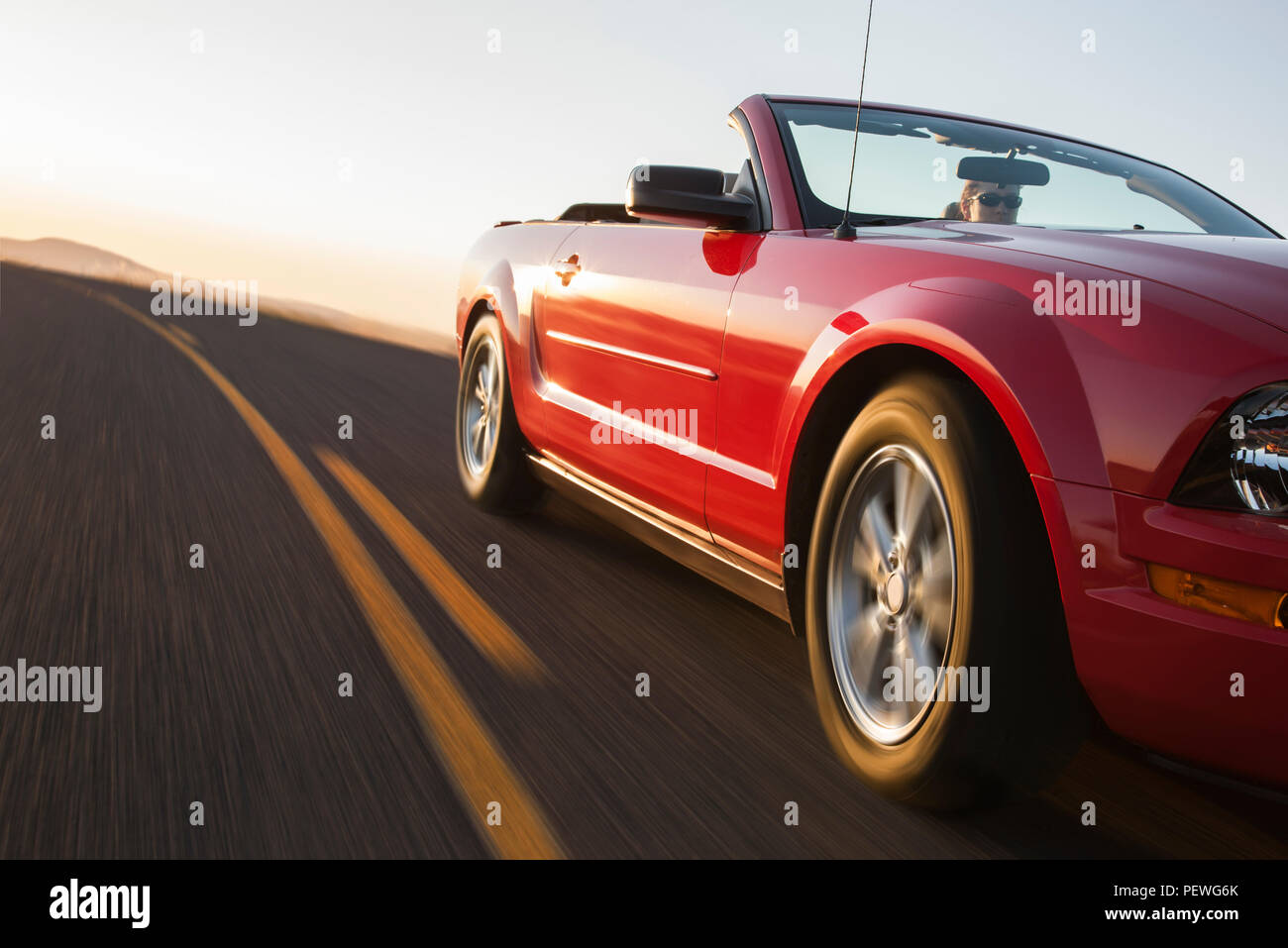 A low angle view of a convertible sports car moving on a highway late ...
