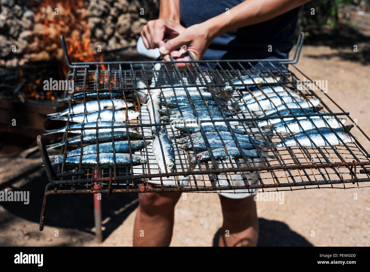 closeup of a young caucasian man about to grill some raw sardines on a ...