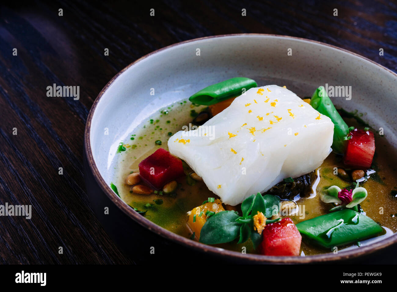 Pouring broth on halibut with lemon, peas, melon, beets and herbs Stock ...