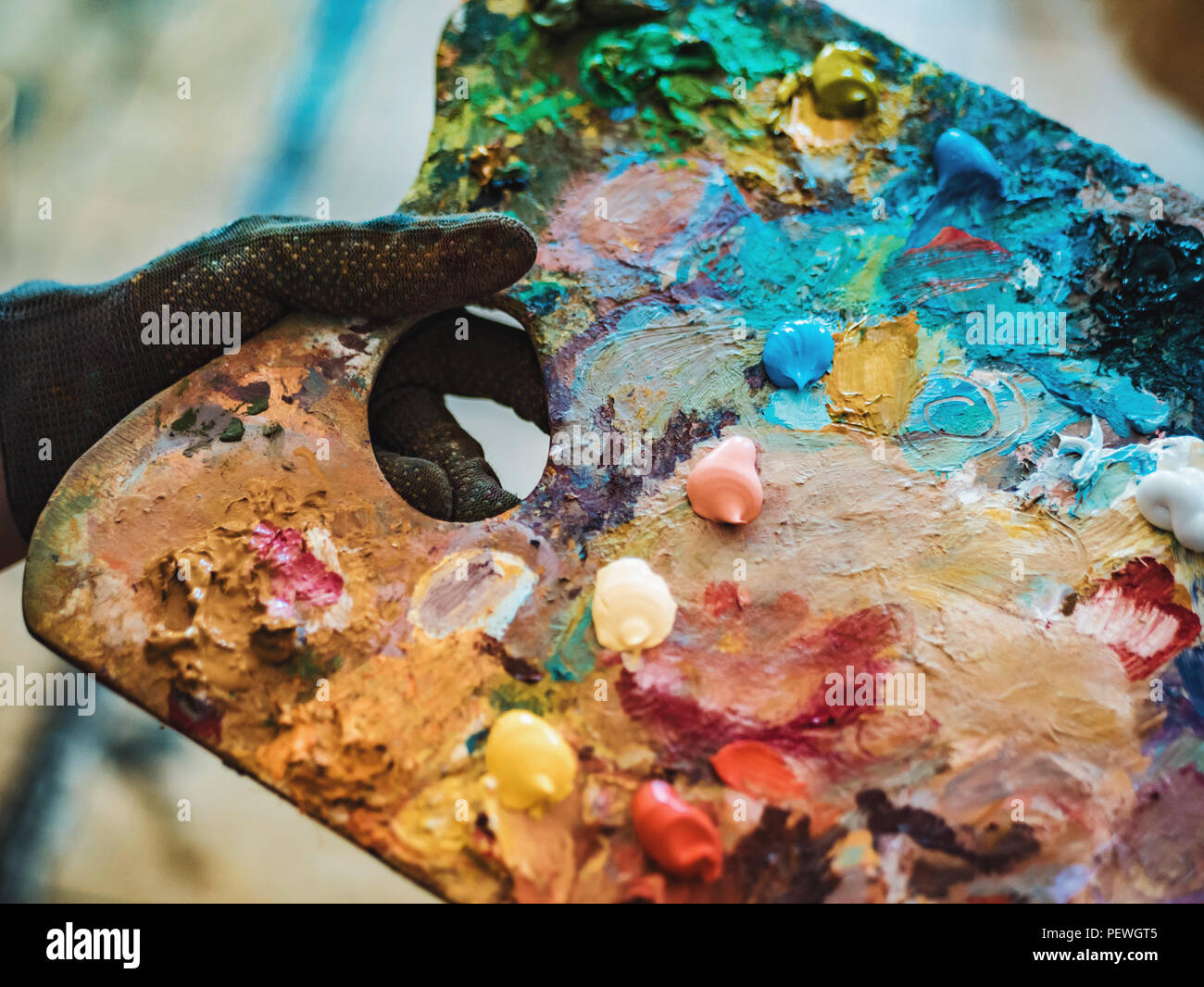 Wooden art palette with oil paints. Mixing colors together. Artistic ...