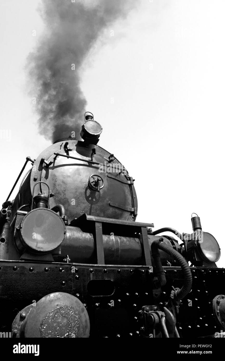 Detail of Vintage steam engine, working, with smoke, against blue sky ...