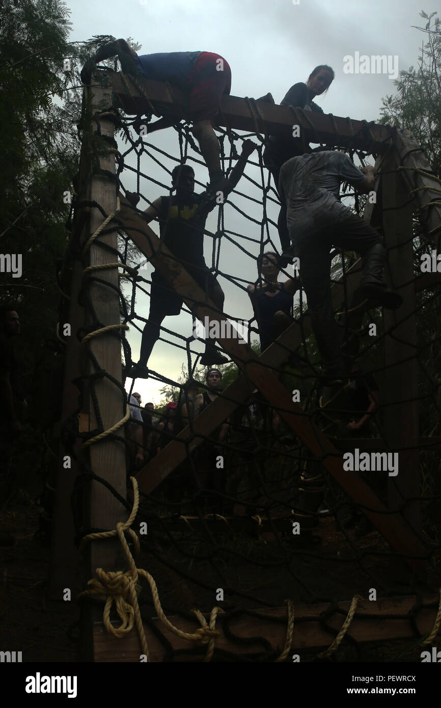 Participants in the 22nd Annual Swamp Romp 5K Mud Run climb over a rope ...