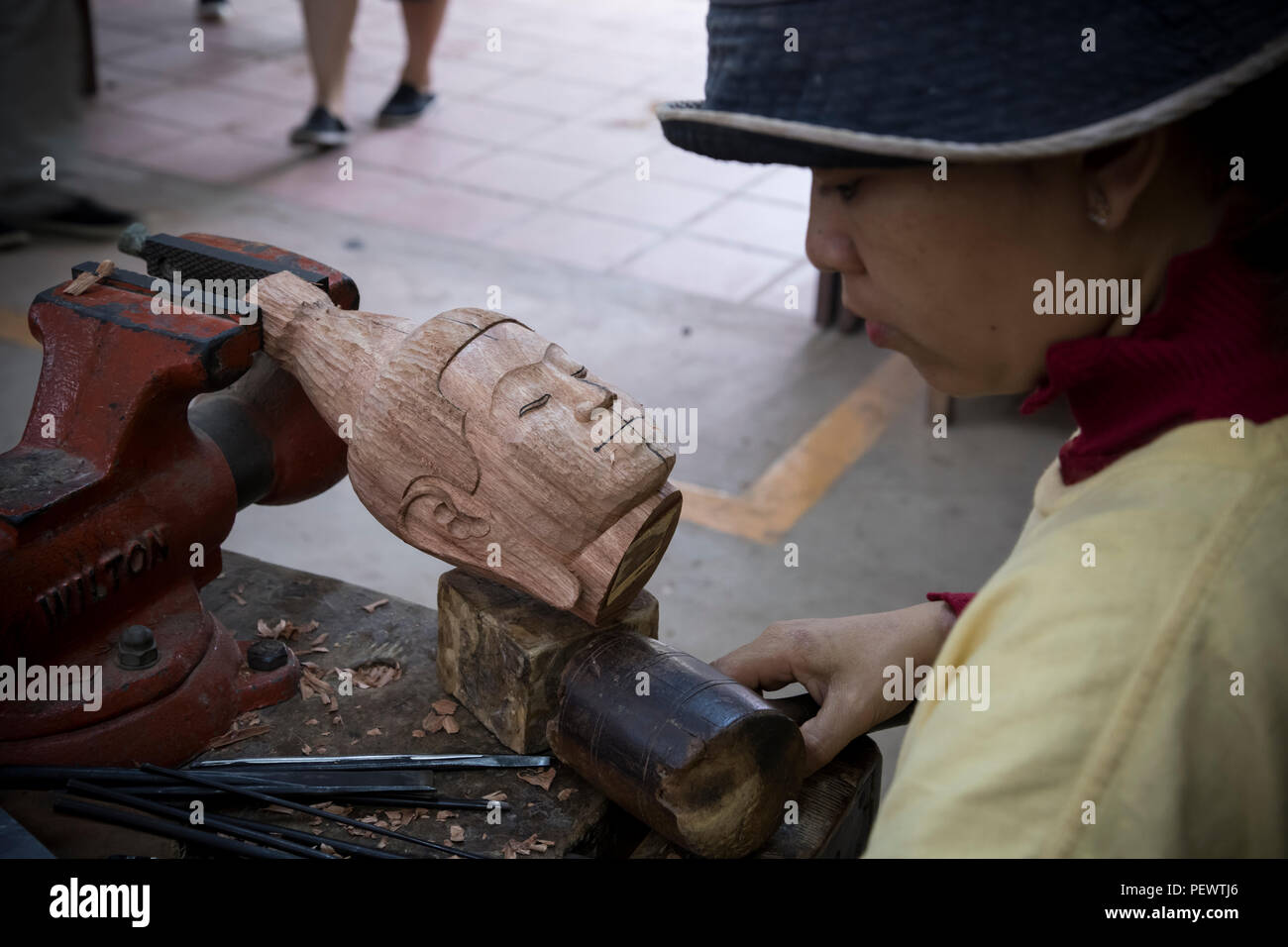 A Cambodian woman carving a wooden Buddha head in an art center, Siem ...