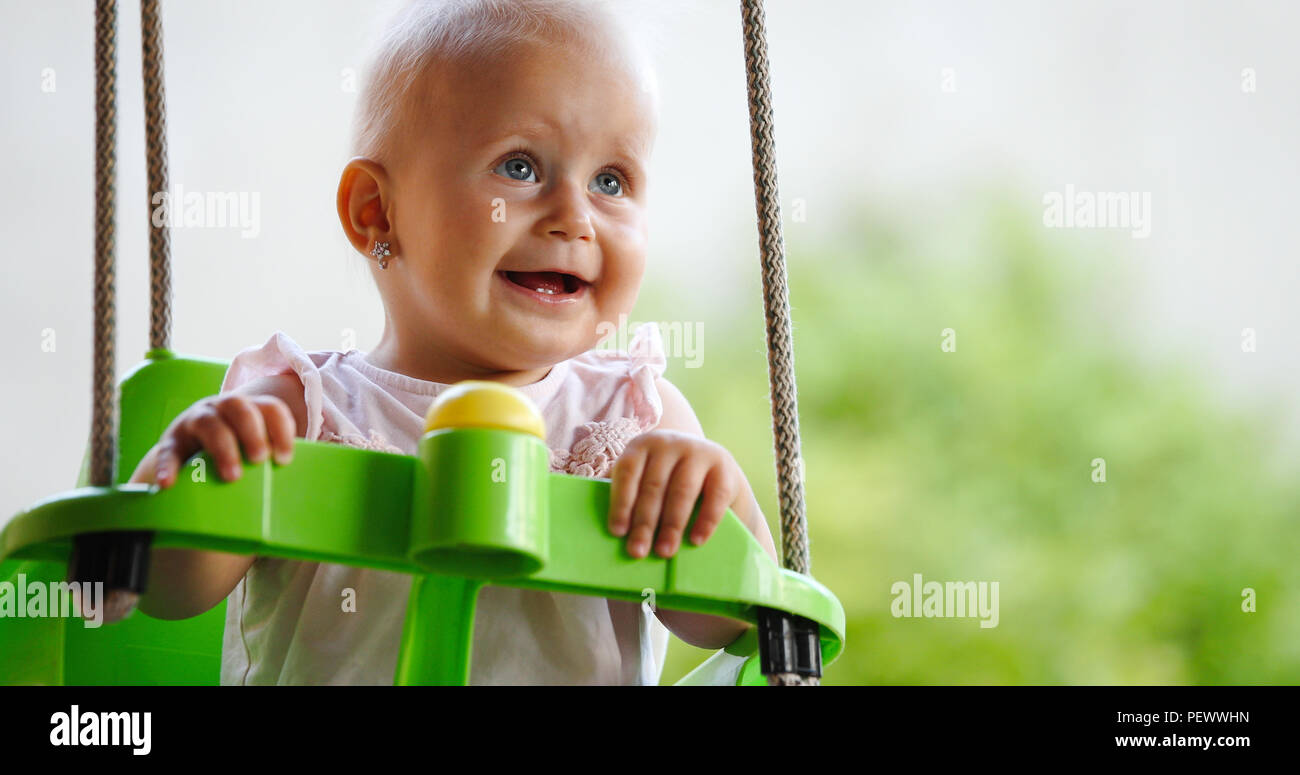 Happy baby enjoying outdoor activities and smiling while swinging Stock ...