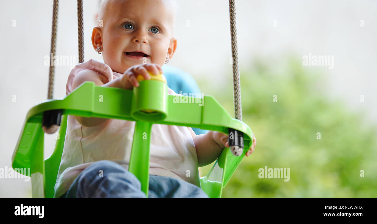 Happy baby enjoying outdoor activities and smiling while swinging Stock ...