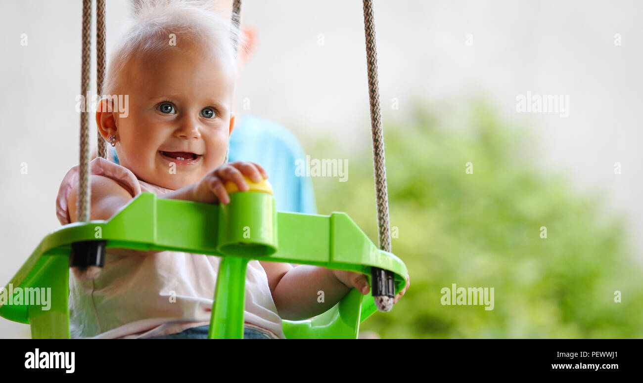Happy baby enjoying outdoor activities and smiling while swinging Stock ...