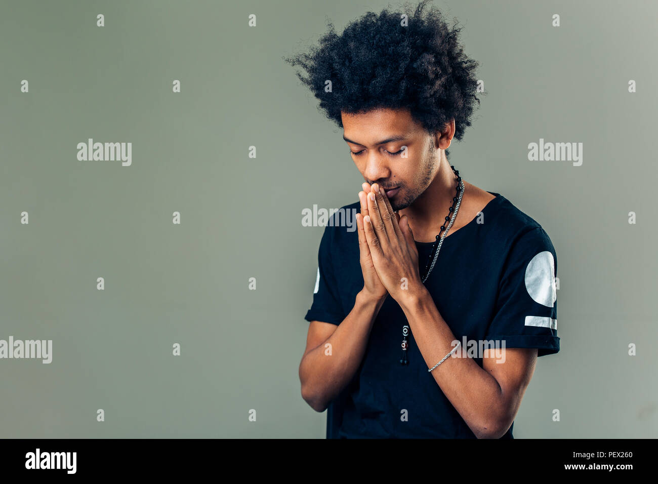 Closeup portrait young man praying hands clasped hoping for best asking ...