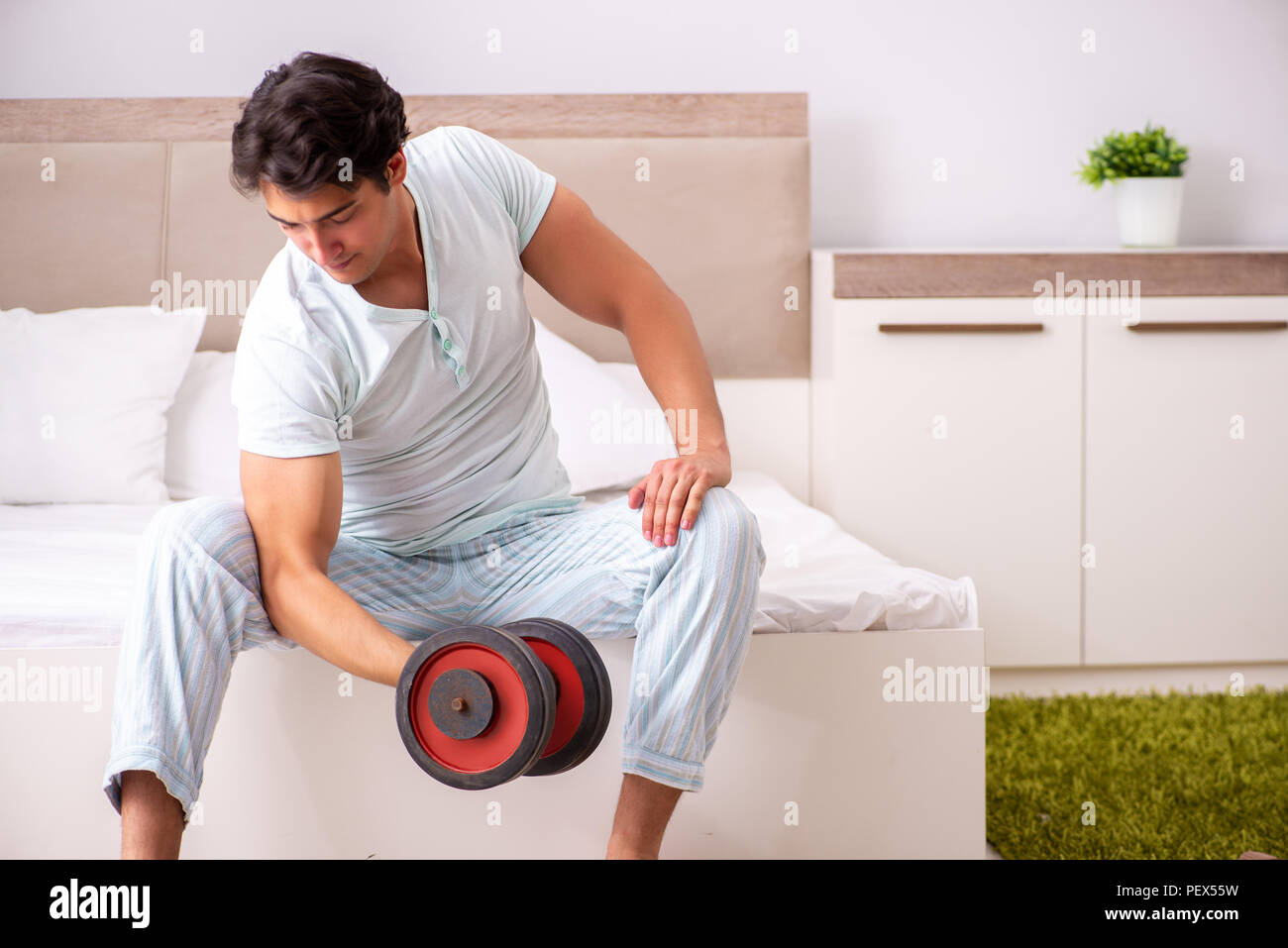 Young man doing morning routine in bedroom Stock Photo - Alamy