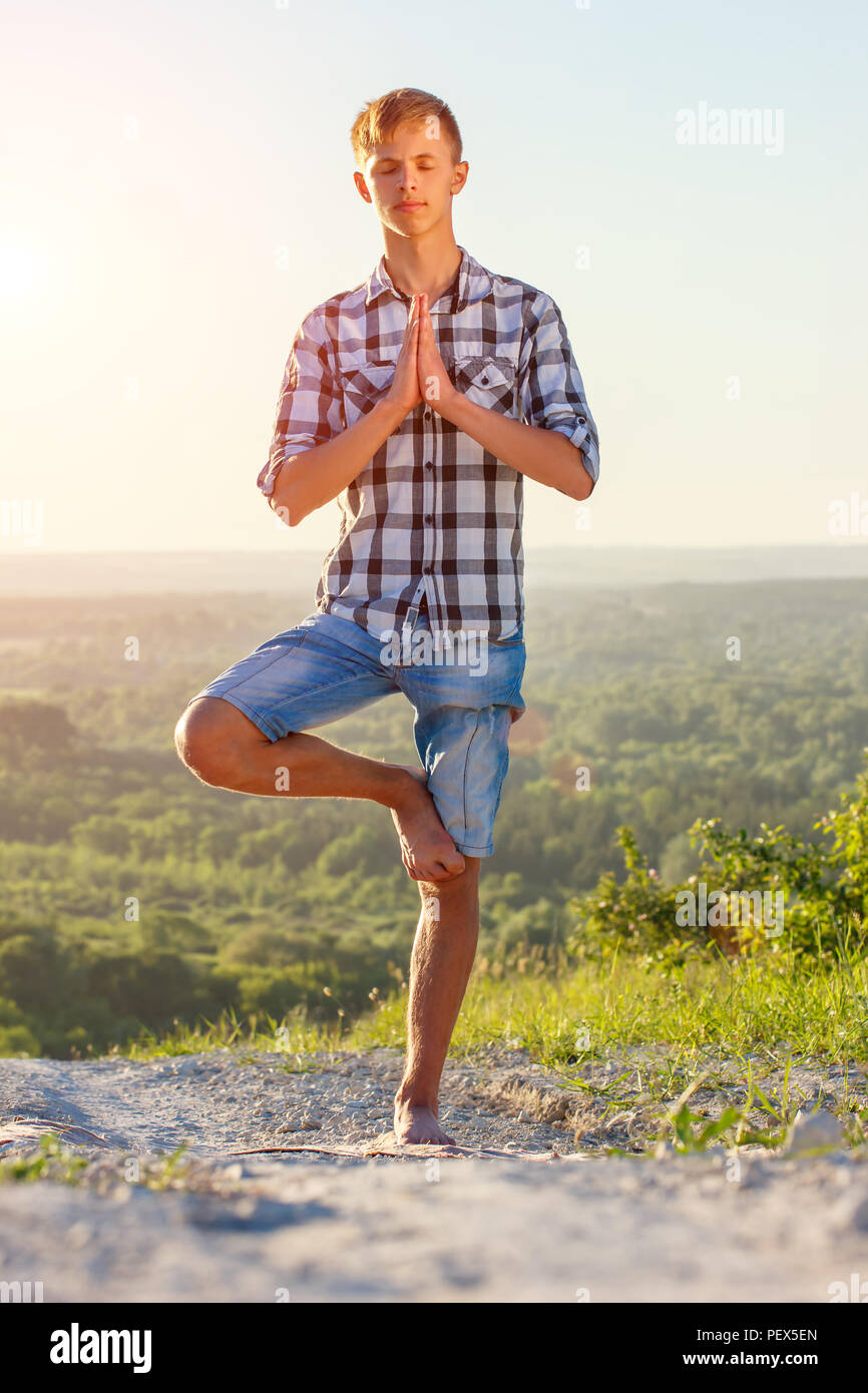 young man doing yoga outdoors in the sun health concept Stock Photo - Alamy