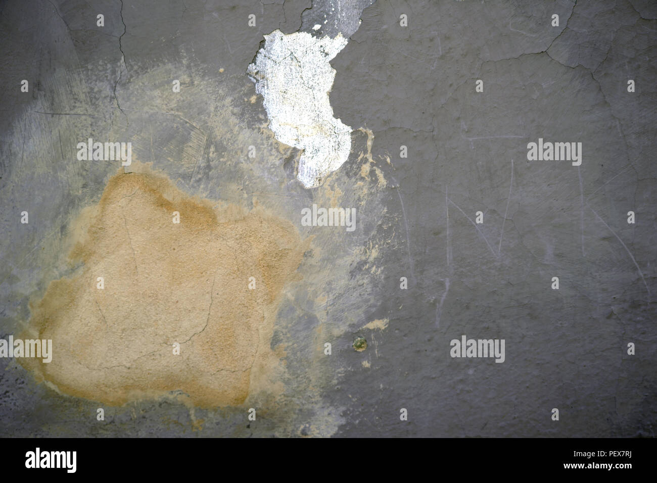 The close-up of a wall with a chipped plaster layer and repair points ...