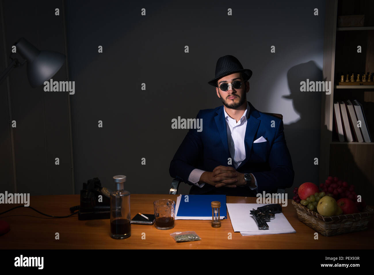 Detective sitting in dark room in vintage concept Stock Photo - Alamy