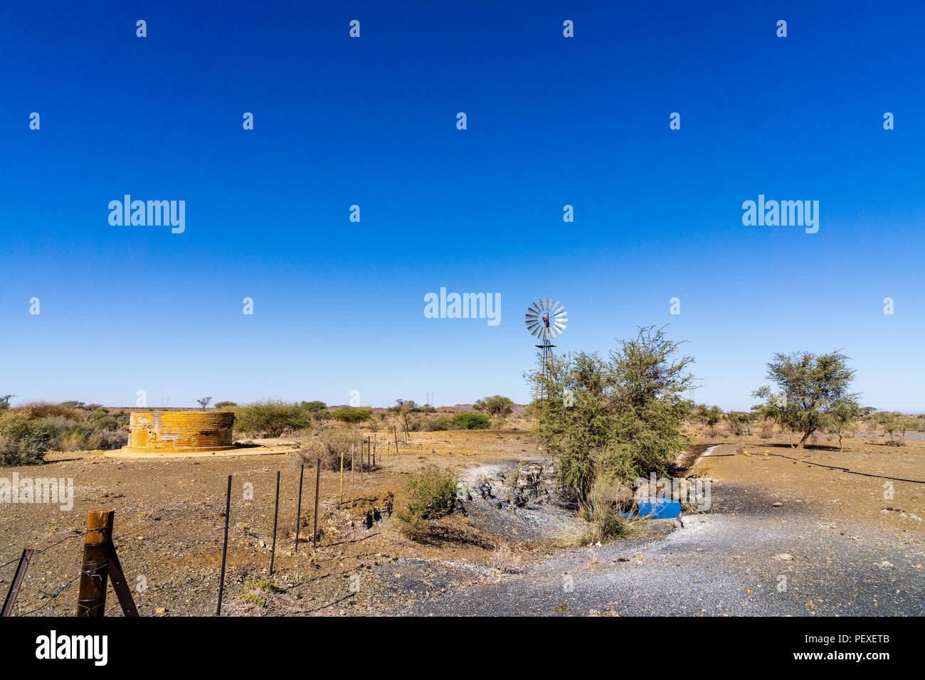 A windmill and water reservoir stand in a remote and desolate landscape ...