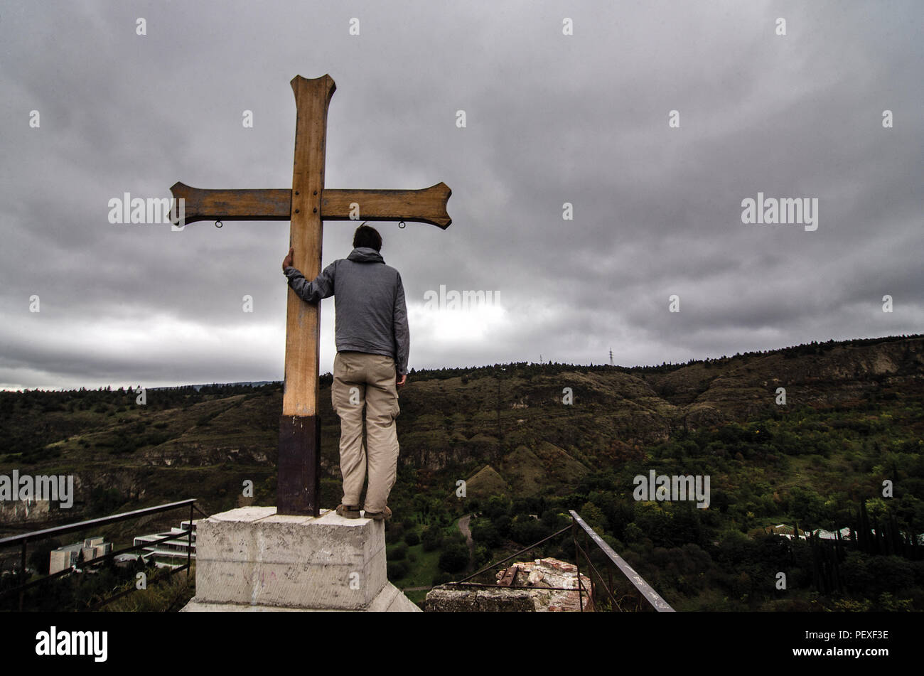The Georgian man holds the Orthodox cross and looks at the Caucasus ...