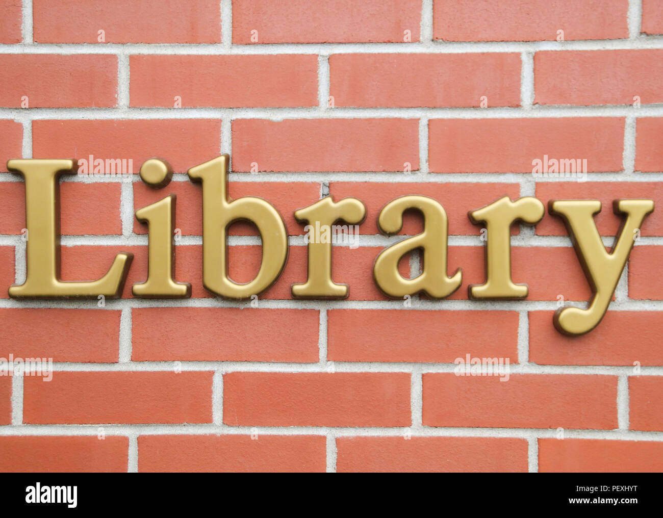 Letters spelling LIBRARY sign in gold on a brick wall Stock Photo - Alamy