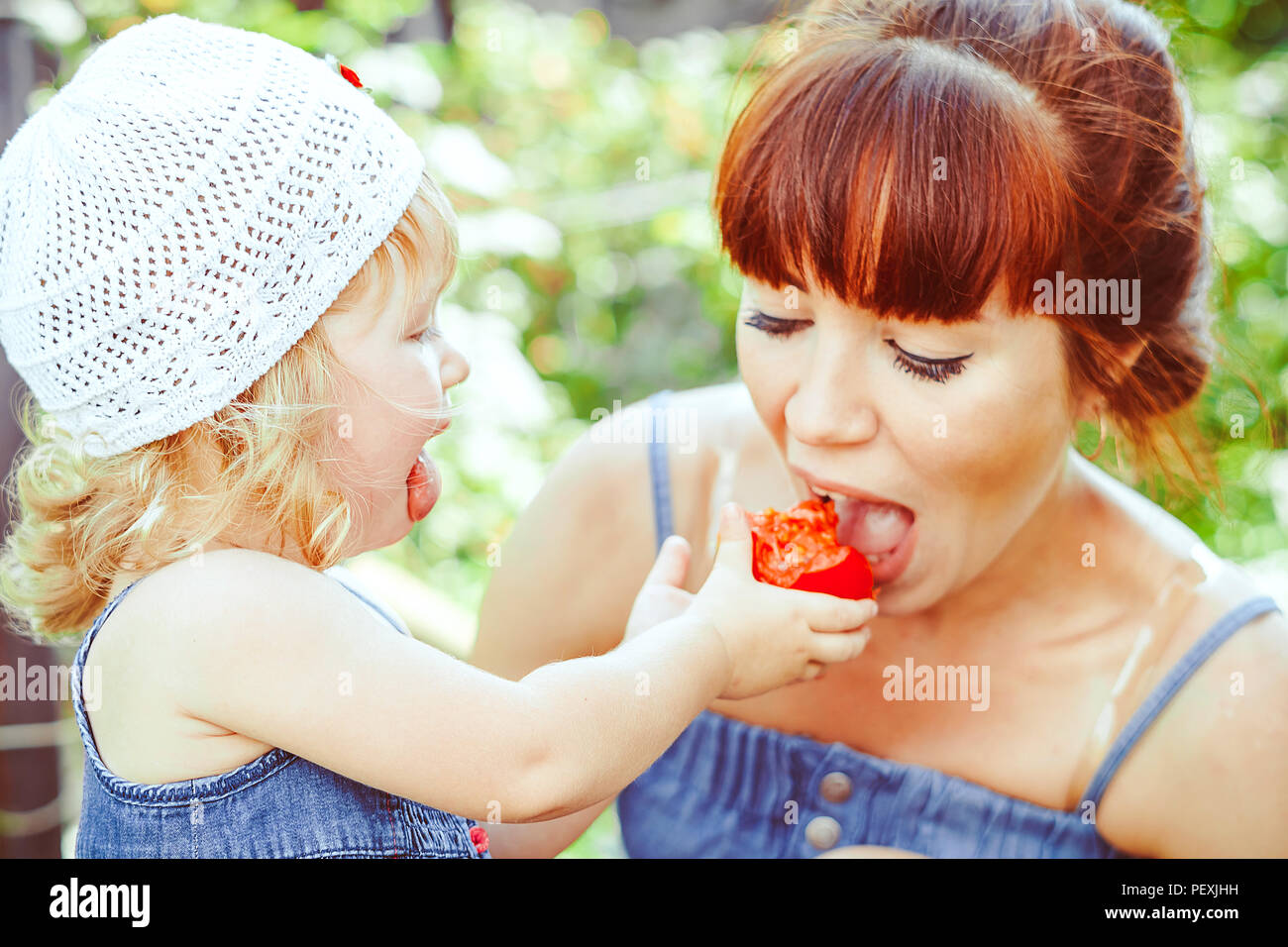 independent kid eating a tomato, standing in nature Stock Photo - Alamy