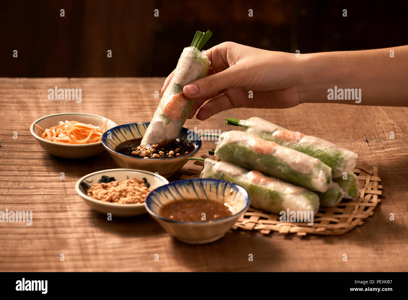 Hand holding Vietnamese spring roll above the bowl with dipping soy ...
