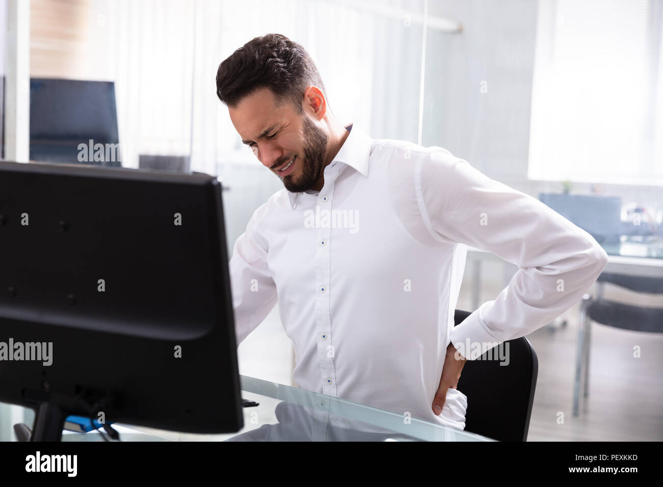 Young Businessman Suffering From Back Pain At Workplace Stock Photo - Alamy