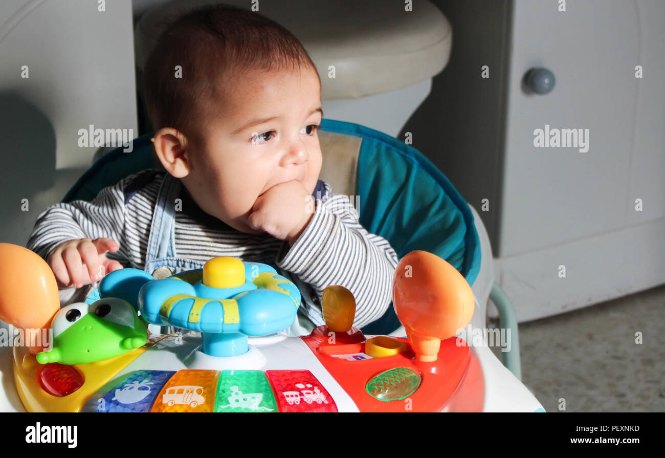 baby boy in the walker, puting his hand in mouth, growing teeth Stock ...