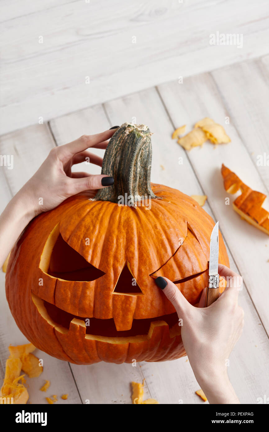 Woman carving big orange pumpkin into jack-o-lantern for Halloween ...