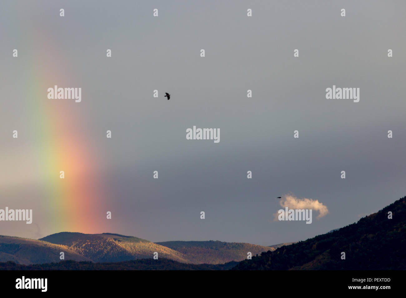 Beautiful and surreal view of part of a rainbow over some hills with ...
